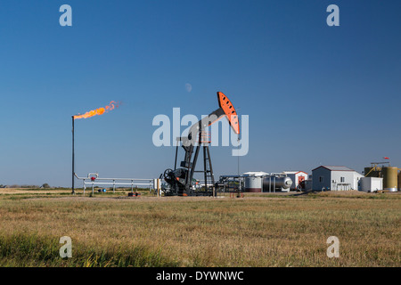 An oil production pumper and flaring gas in the Bakken field near ...
