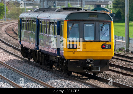 Class 142 diesel train on Arriva Trains Wales service to Barry Island passing car park of ...