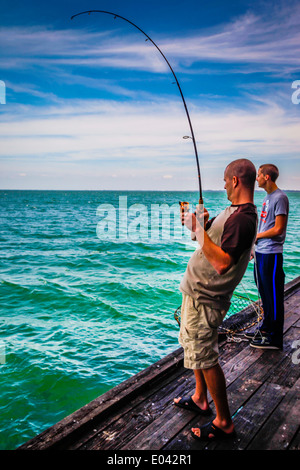 Fisherman reeling in his catch which fights against being landed as the ...