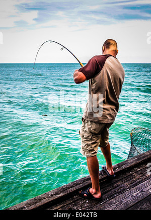 Fisherman reeling in his catch which fights against being landed as the ...