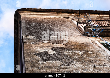 An old weathered corner building seen from the street with vehicles in ...
