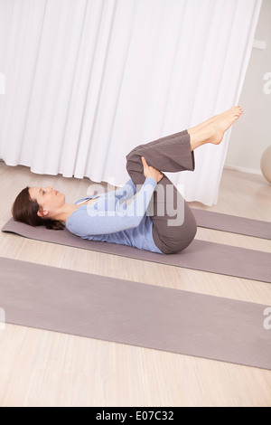 Woman doing Pilates exercise, lying on back Stock Photo - Alamy
