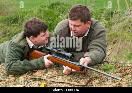 A young boy with an air rifle being coached in target shooting by his ...