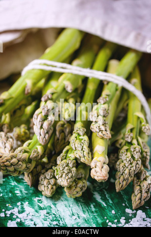 Fresh asparagus bunch and sea salt on gray napkin on green table ...
