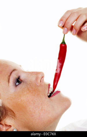 A young woman bites in a Chilli pod. Before white background, Eine ...