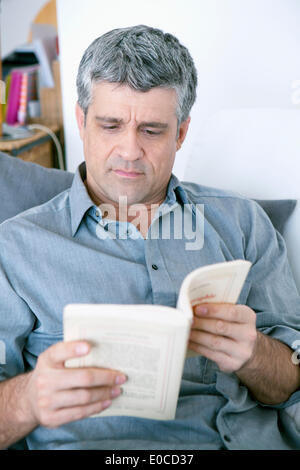 A man sits alone, inside, reading his e-book Stock Photo - Alamy