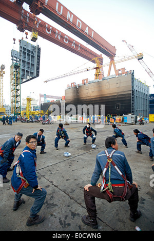 Shipyard workers doing morning exercises before shift, modular ...