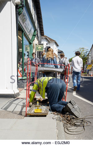 Openreach engineer working on pavement sited telephone junction box ...