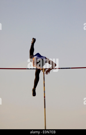 A High School track athlete jumps over the bar during the high jump ...