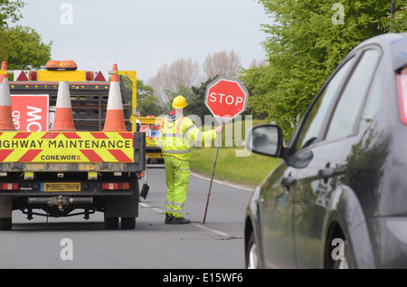 construction worker using lollipop stop - go sign to control traffic at ...