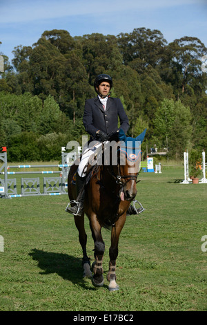 Male in helmet riding by horse at farm, trainer talking to woman in ...