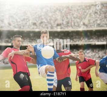 Soccer player reaching for ball, opponent jumping over leg, blurred ...