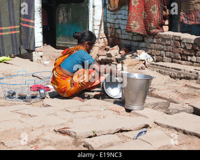 Young Indian woman washing dishes outside their rural indian village ...