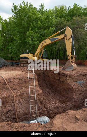 Working excavator tractor digging a trench for pipenlineat at ...