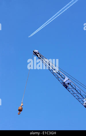Crane and high flying jet plane in blue sky Stock Photo - Alamy
