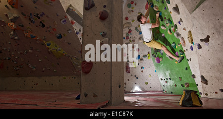 Man bouldering at an indoor climbing centre. Climber practicing rock ...