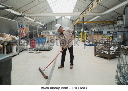 Worker with broom in manufacturing plant Stock Photo - Alamy