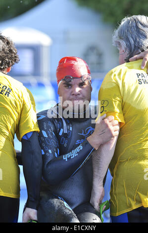 Swimmer with red cap and black wetsuit, equipped with orange buoy, runs ...