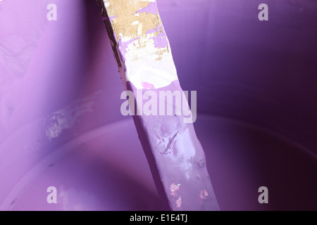 Purple paint bucket with mixing stick Stock Photo - Alamy