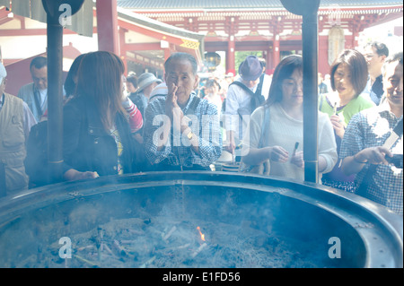 Tokyo, Japan - 2014 - Japaneese people wafting smoke from incense ...