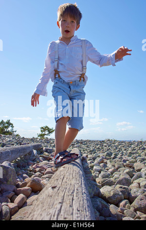 Boy standing on a log at the beach Stock Photo - Alamy
