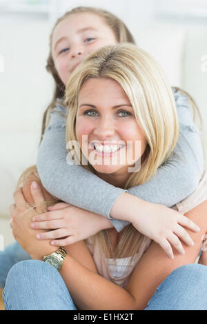 Daughter hugging her mother from behind both staring forward with a ...