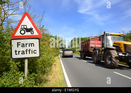 tractor and trailer passing warning sign of farm traffic in road ahead ...