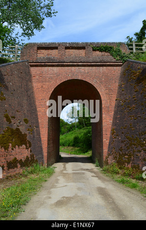 High arched brick railway bridge spanning a quiet road in Blisworth ...