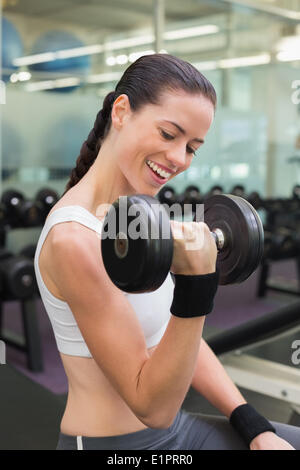 Fit smiling brunette lifting heavy black dumbbell Stock Photo - Alamy