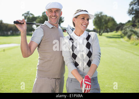 Golfing couple smiling and holding clubs Stock Photo - Alamy