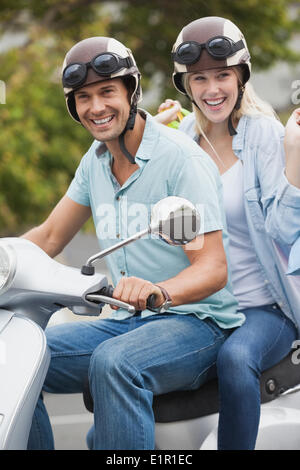 Cheerful young couple riding a scooter and having fun Stock Photo - Alamy