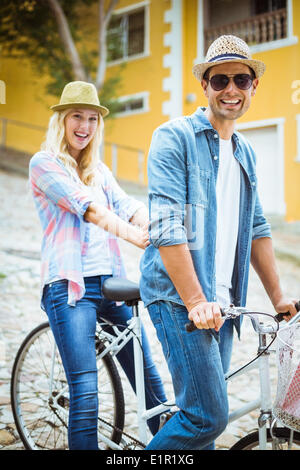 Smiling young couple going for a bike ride on a sunny day in the city ...