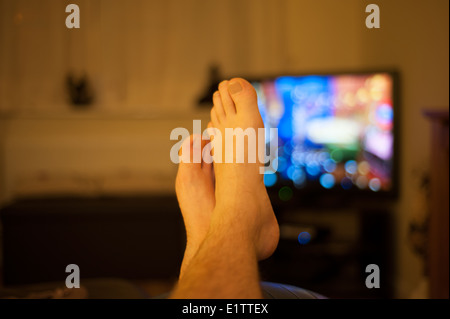 A man's bare feet and legs. Relaxing in a field of grass and yellow ...