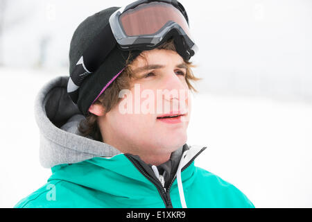 A young man wearing winter clothing and a blanket while using his ...