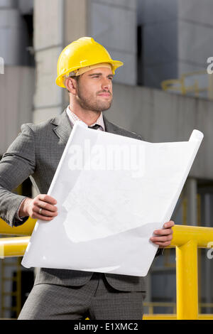 Young male engineer with blueprint on blue background Stock Photo - Alamy