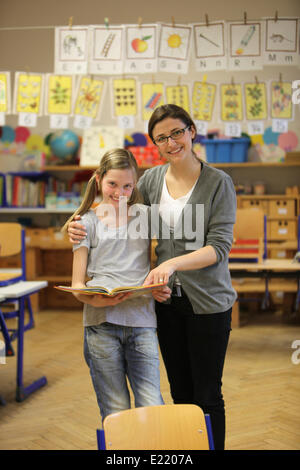 Smiling teacher writing letters on whiteboard and asking pupils to name ...