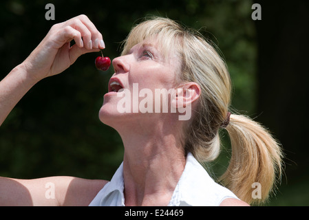 Woman eating cherries Stock Photo - Alamy