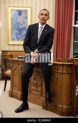 President Barack Obama sits on the edge of the Resolute Desk in the ...