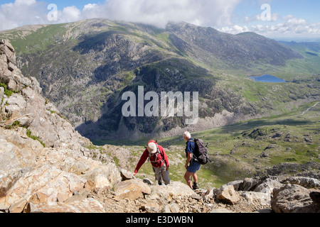 Hikers scrambling walking up red rocks of Crib Goch at start of Snowdon ...