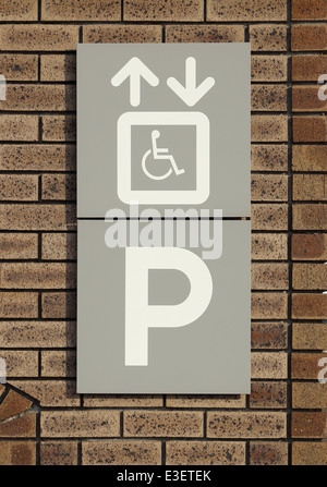 Handicapped sign on brick wall showing the direction of the wheelchair ...