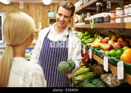 Male shopping assistant helping customer to buy pomegranate fruit in ...