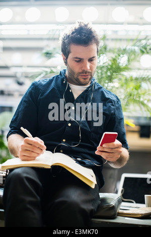 Businessman holding pen writing book note on desk with computer laptop ...