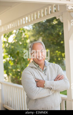 Smiling mature man with arms crossed leaning on tree Stock Photo - Alamy