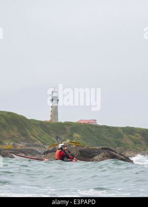 USA, Washington State, Woman sea kayaker in rock garden in moderate ...