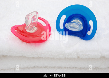 red and blue pacifiers on white towel Stock Photo - Alamy