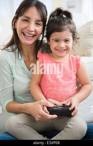 Mature hispanic woman playing video games at home sticking tongue out ...
