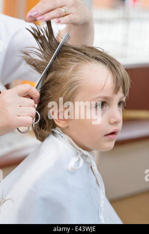 Cute kid boy have hair cut, professional barber doing haircut ...