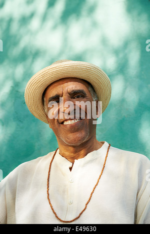 Glad senior man in straw hat smiling and looking at camera while ...