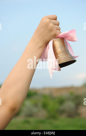 Human hand holding ringing handbell through ripped paper. Hand gestures ...