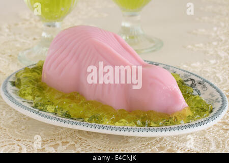 Pink blancmange in the shape of a rabbit on green jelly grass an old ...